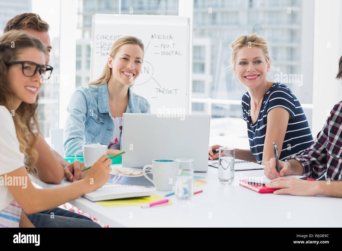 Young casual business people sitting around conference table in a ...