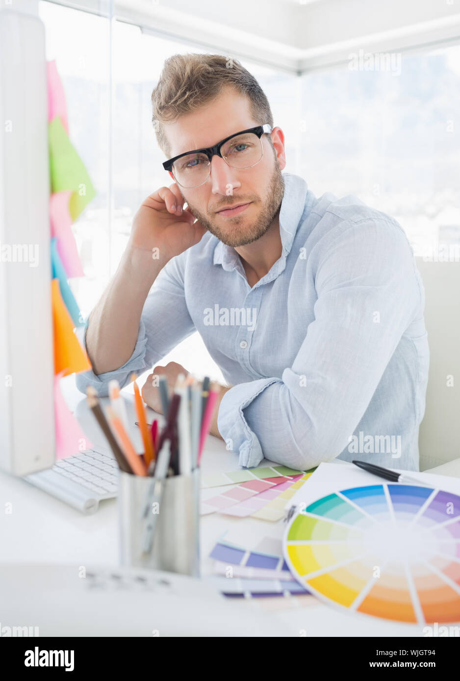 Portrait of a serious young man using computer in a bright office Stock ...