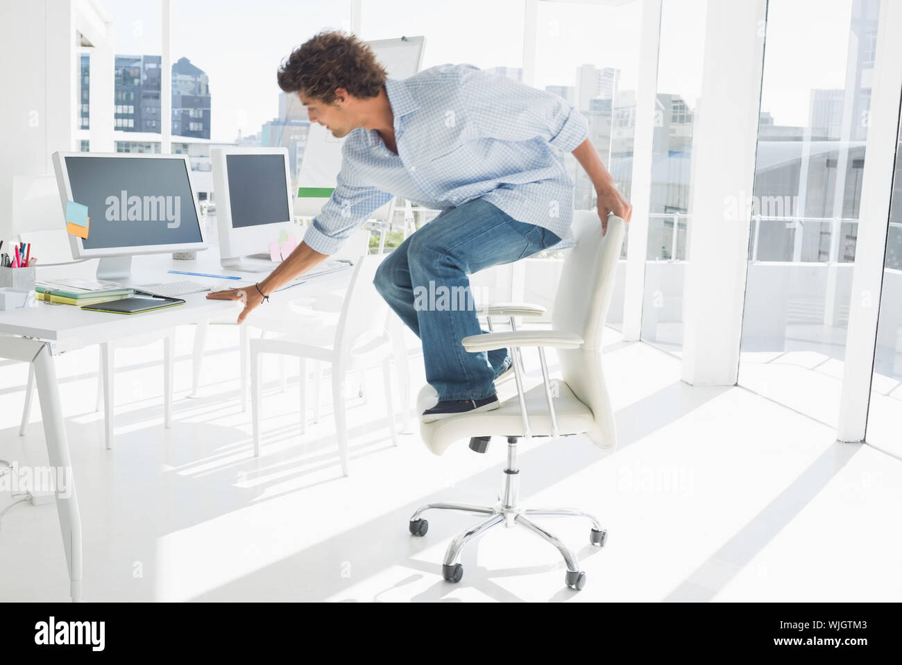 Full length of a young man standing over chair in a bright office Stock ...