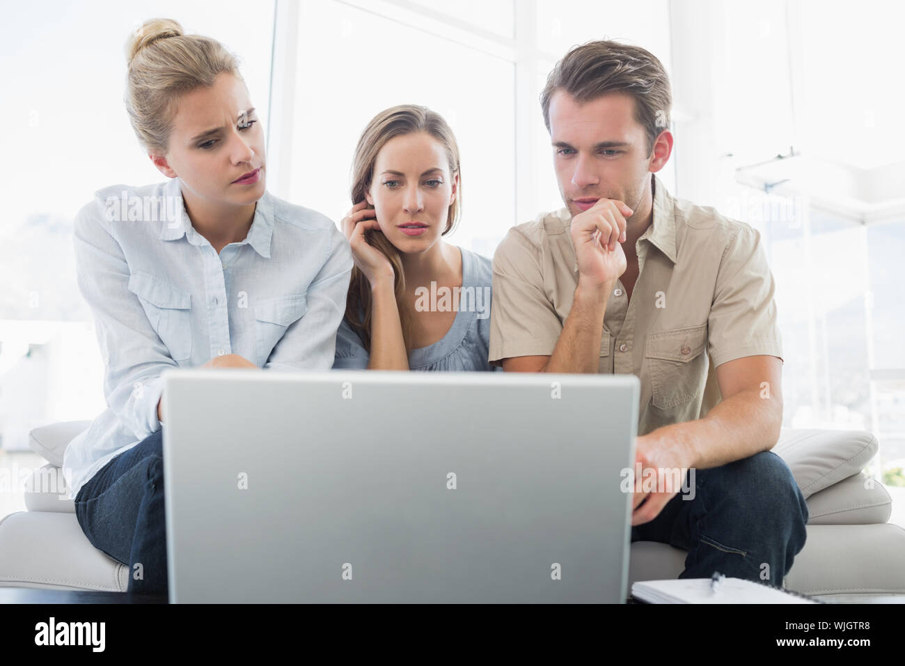 Three young people working on computer in a bright office Stock Photo ...