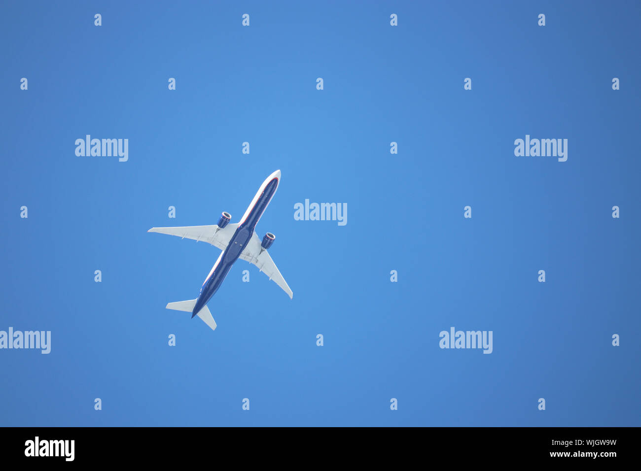 Airplane flying in the clear blue sky, bottom view. Commercial plane ...