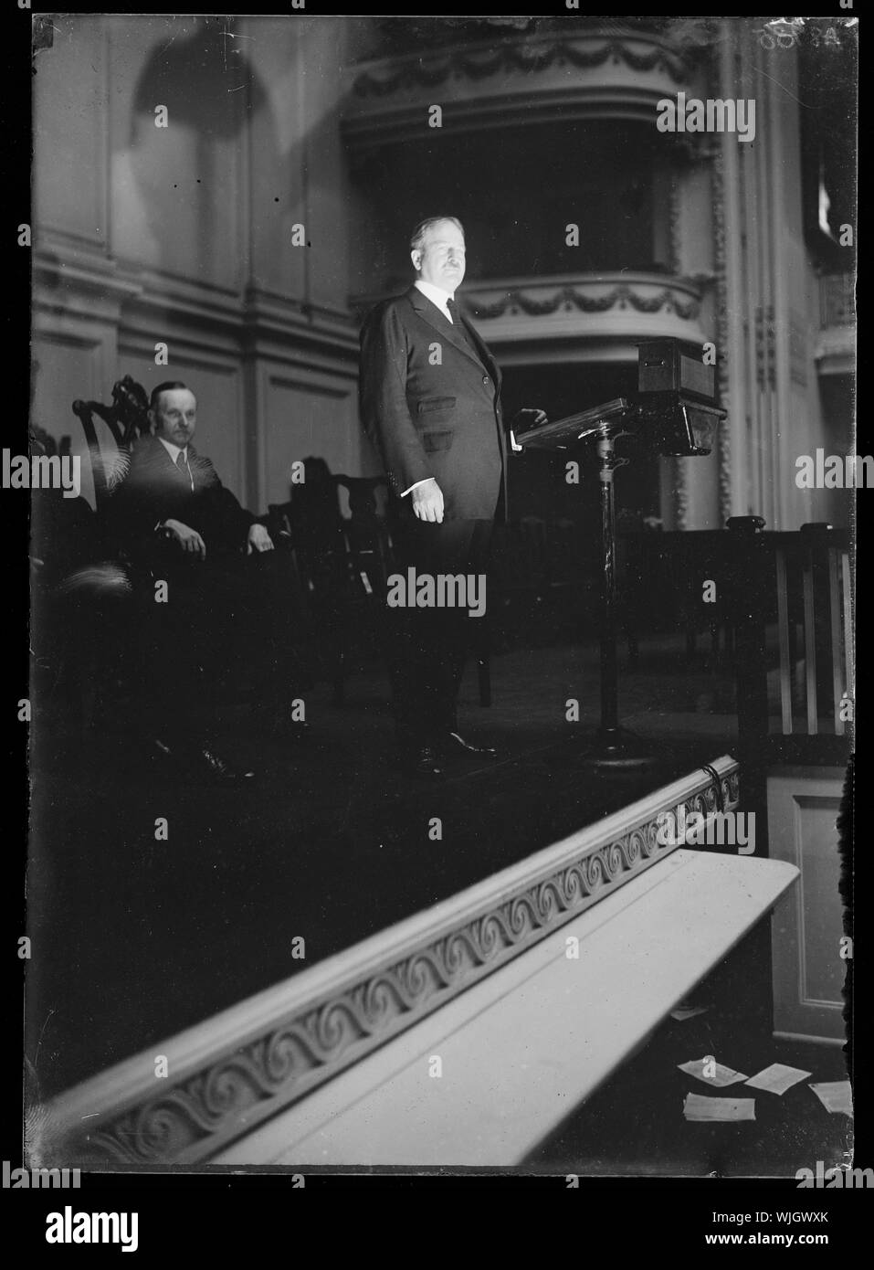 Henry Stimson? at podium on stage with Calvin Coolidge seated in back ...