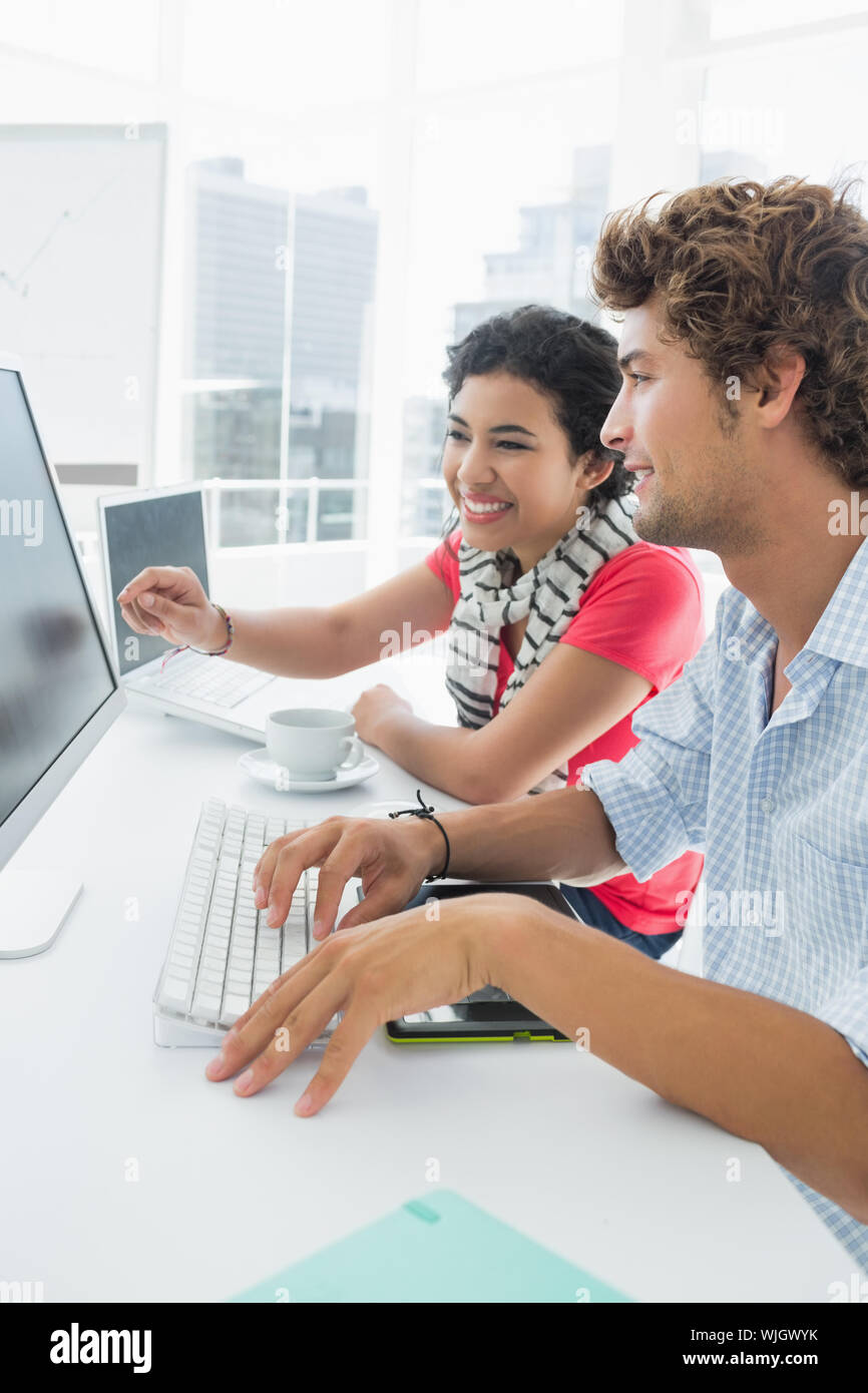 Side view of a casual couple using computer in a bright office Stock ...