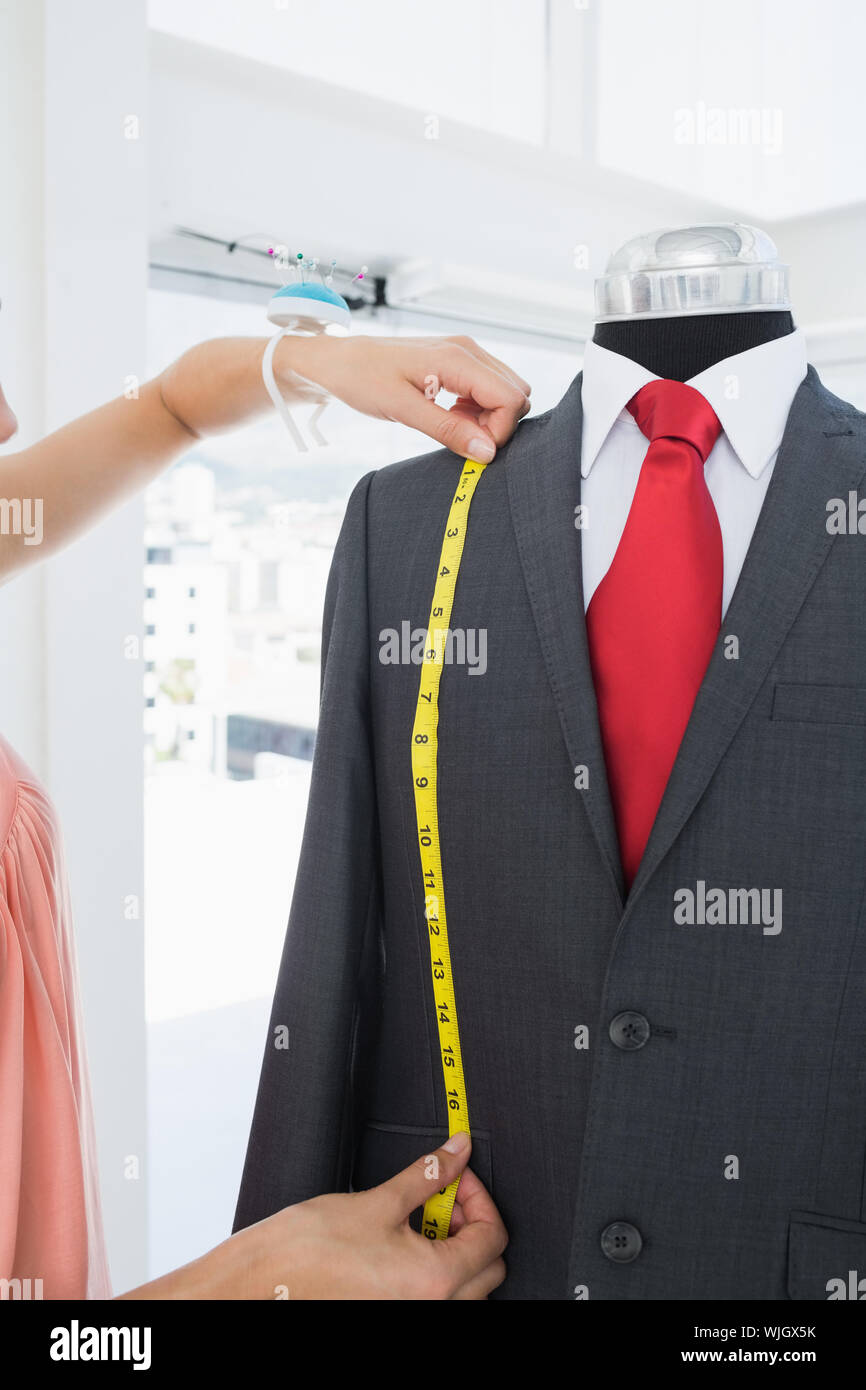 Extreme close-up of a female fashion designer measuring suit on dummy ...