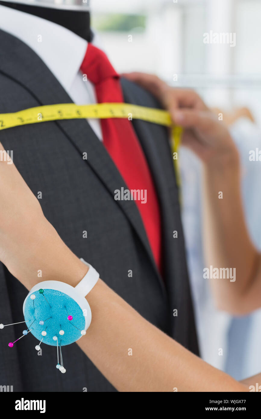 Extreme close-up of a female fashion designer measuring suit on dummy ...