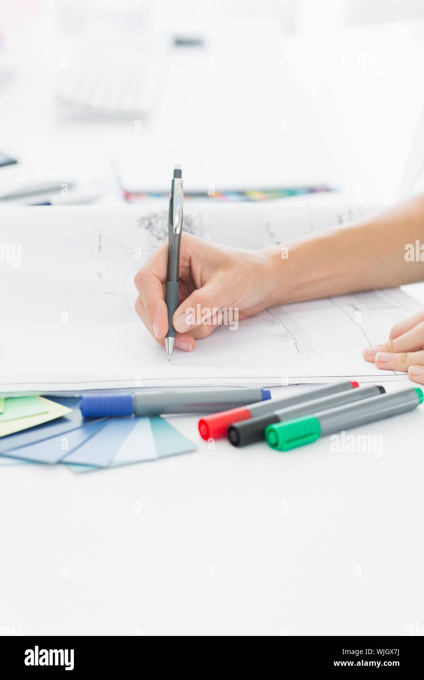 Close-up side view of an artist drawing something on paper with pen at ...