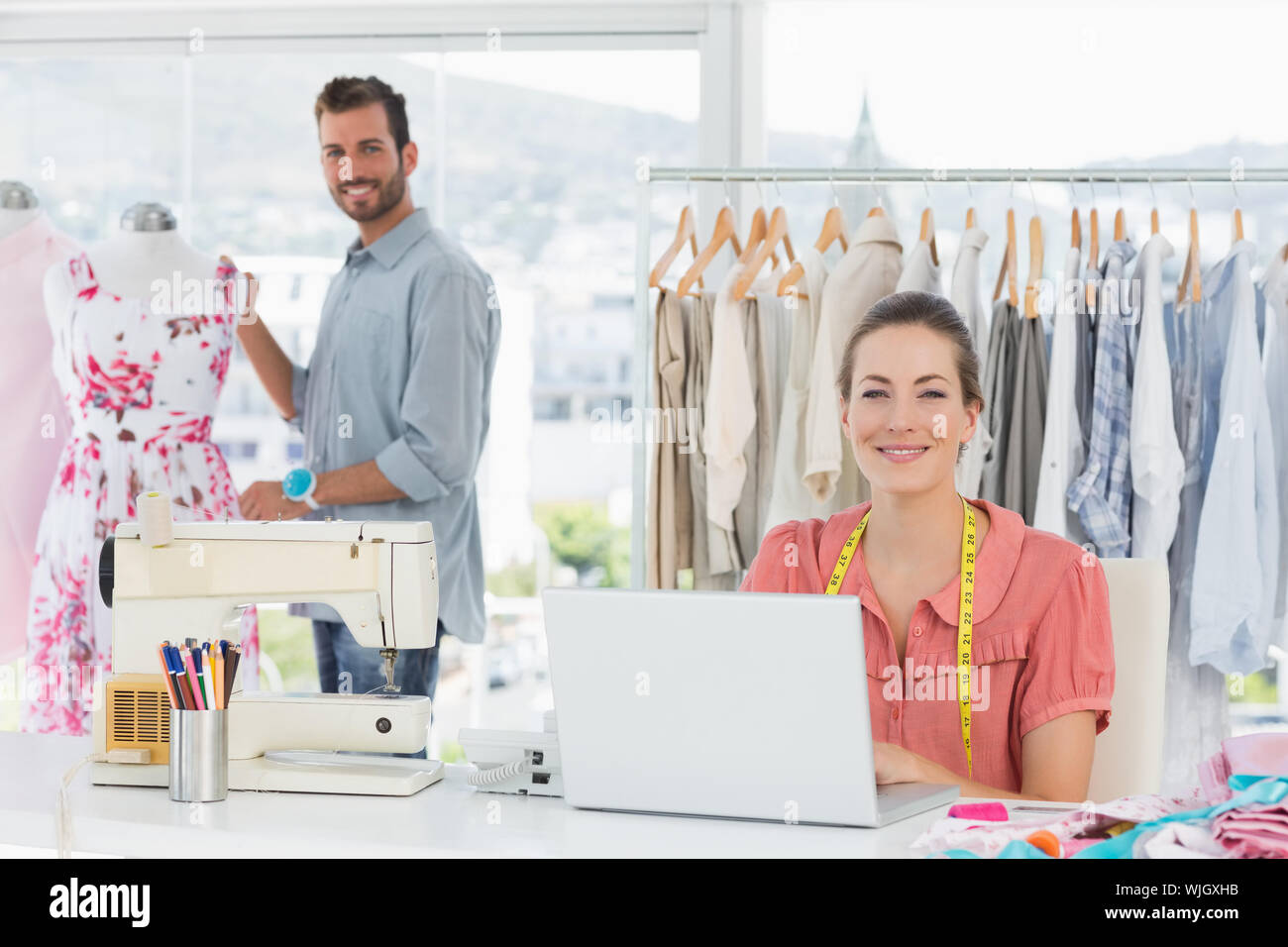 Young woman using laptop with male fashion designer working in ...