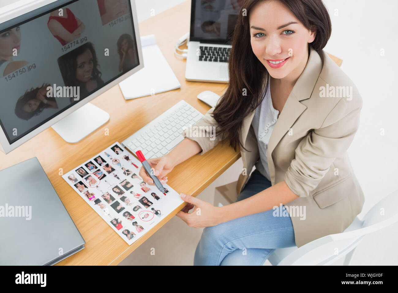 High angle portrait of a female artist sitting at desk with computers ...