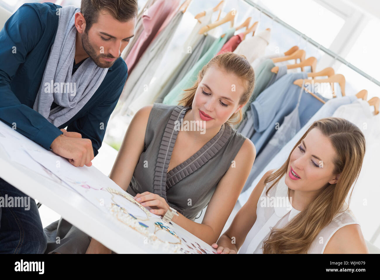 Three fashion designers discussing designs in a studio Stock Photo - Alamy