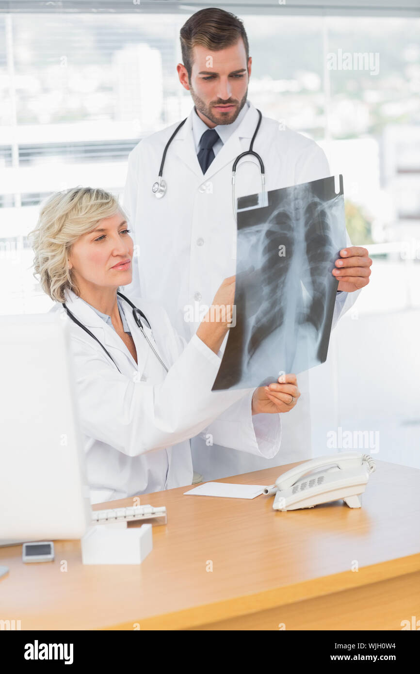 Female doctor explaining x-ray to her male colleague at medical office ...
