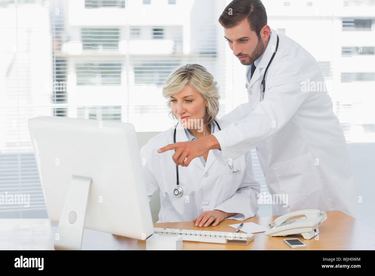 Two concentrated doctors using computer at medical office Stock Photo ...