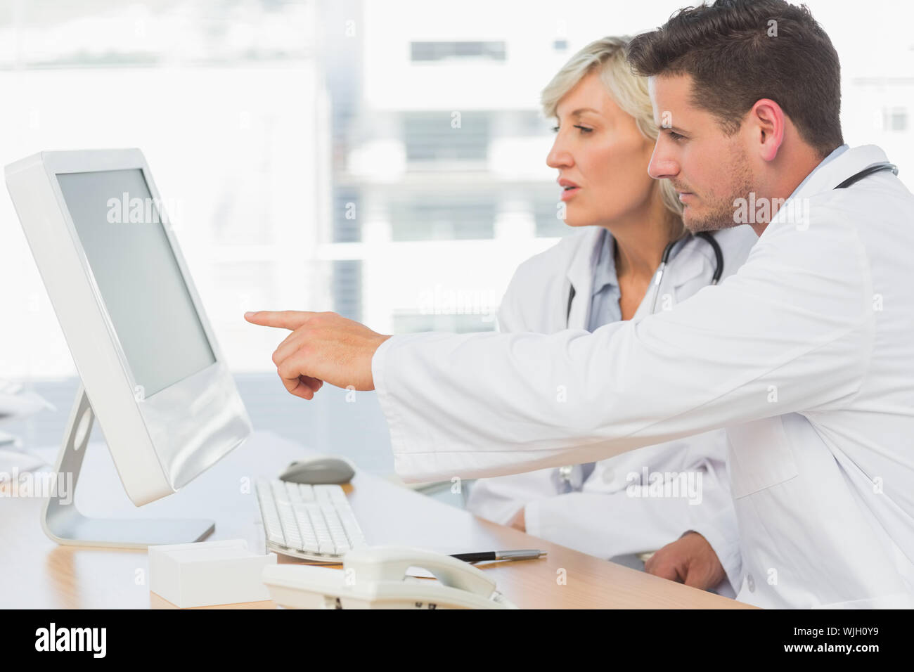 Two concentrated doctors using computer at medical office Stock Photo ...