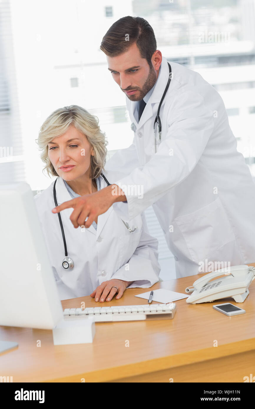 Two concentrated doctors using computer at medical office Stock Photo ...