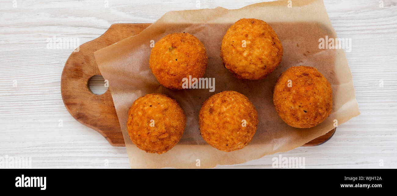 Homemade fried Arancini on a rustic wooden board on a white wooden ...