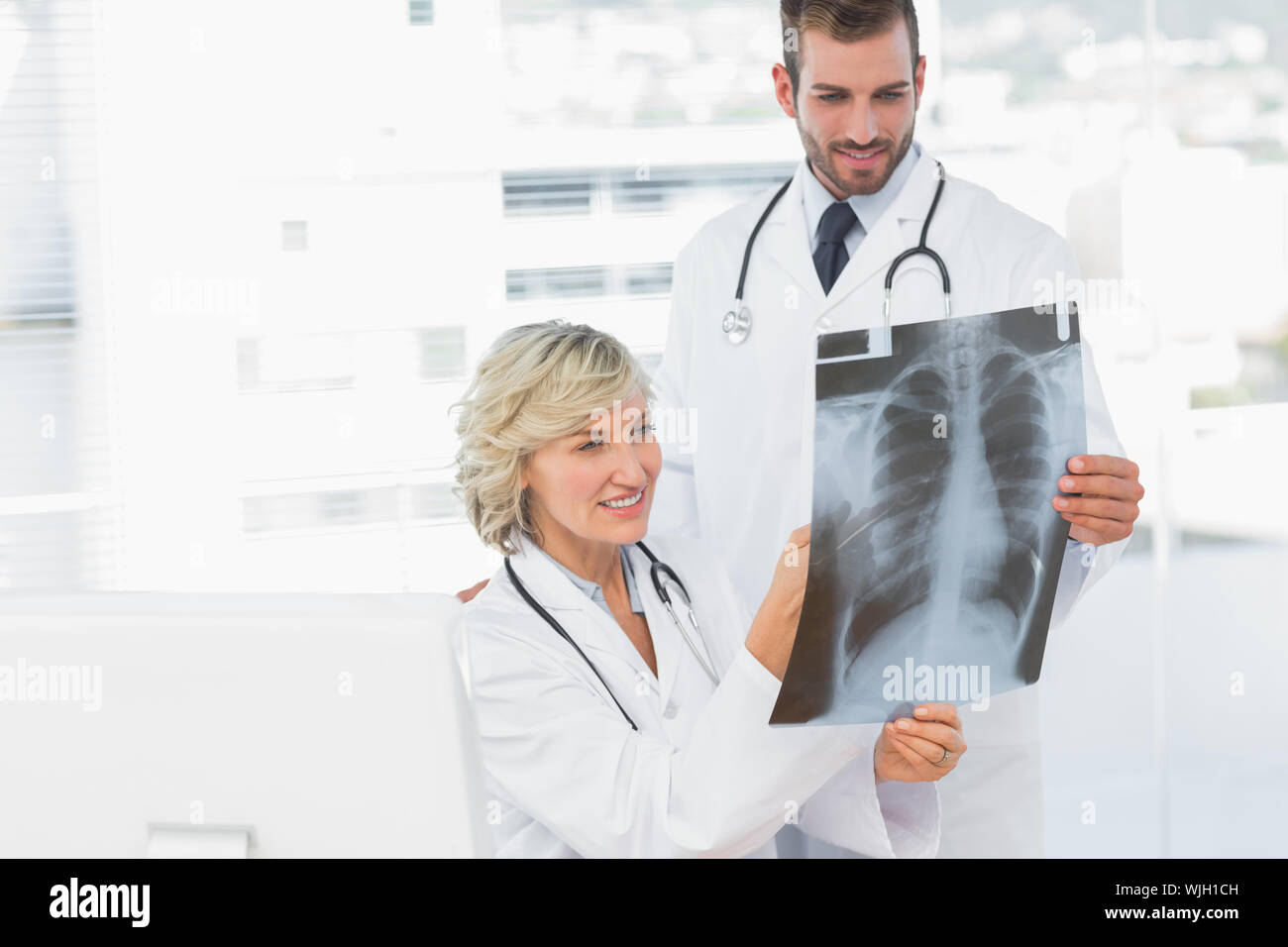Female doctor explaining x-ray to her male colleague at medical office ...