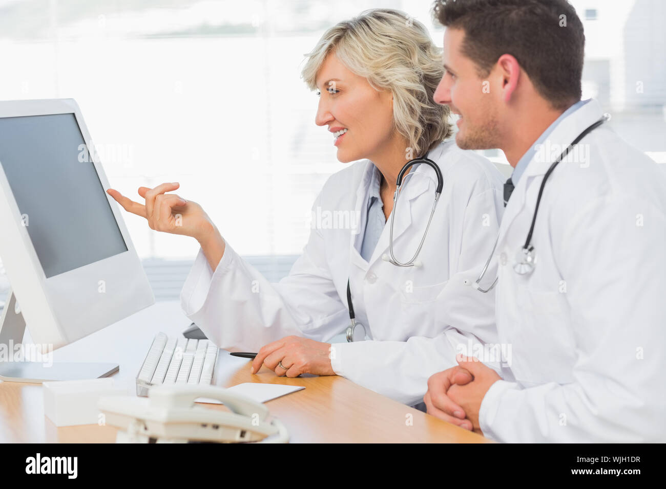 Two concentrated doctors using computer at medical office Stock Photo ...