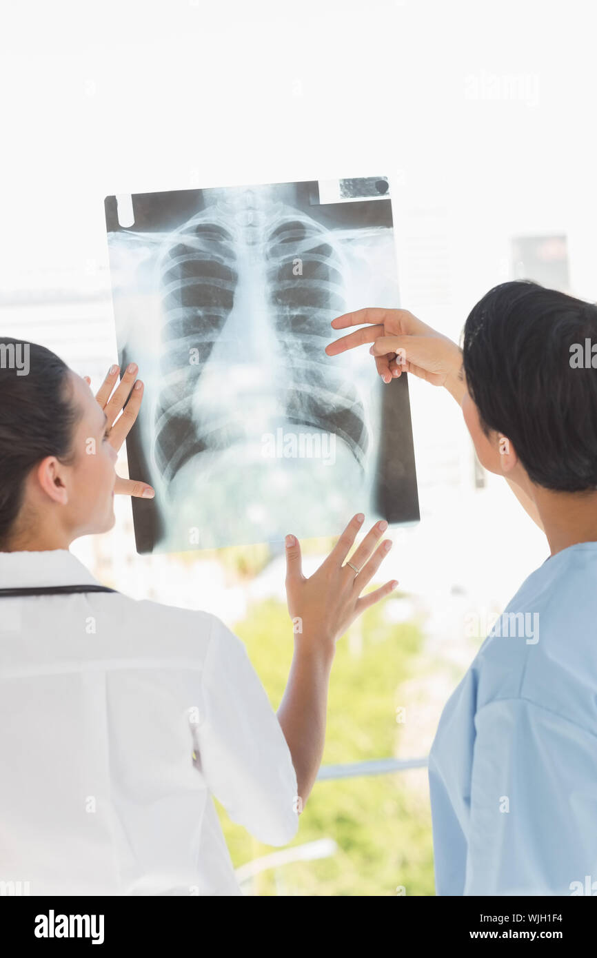 Rear view of two female doctors examining x-ray in the medical office ...
