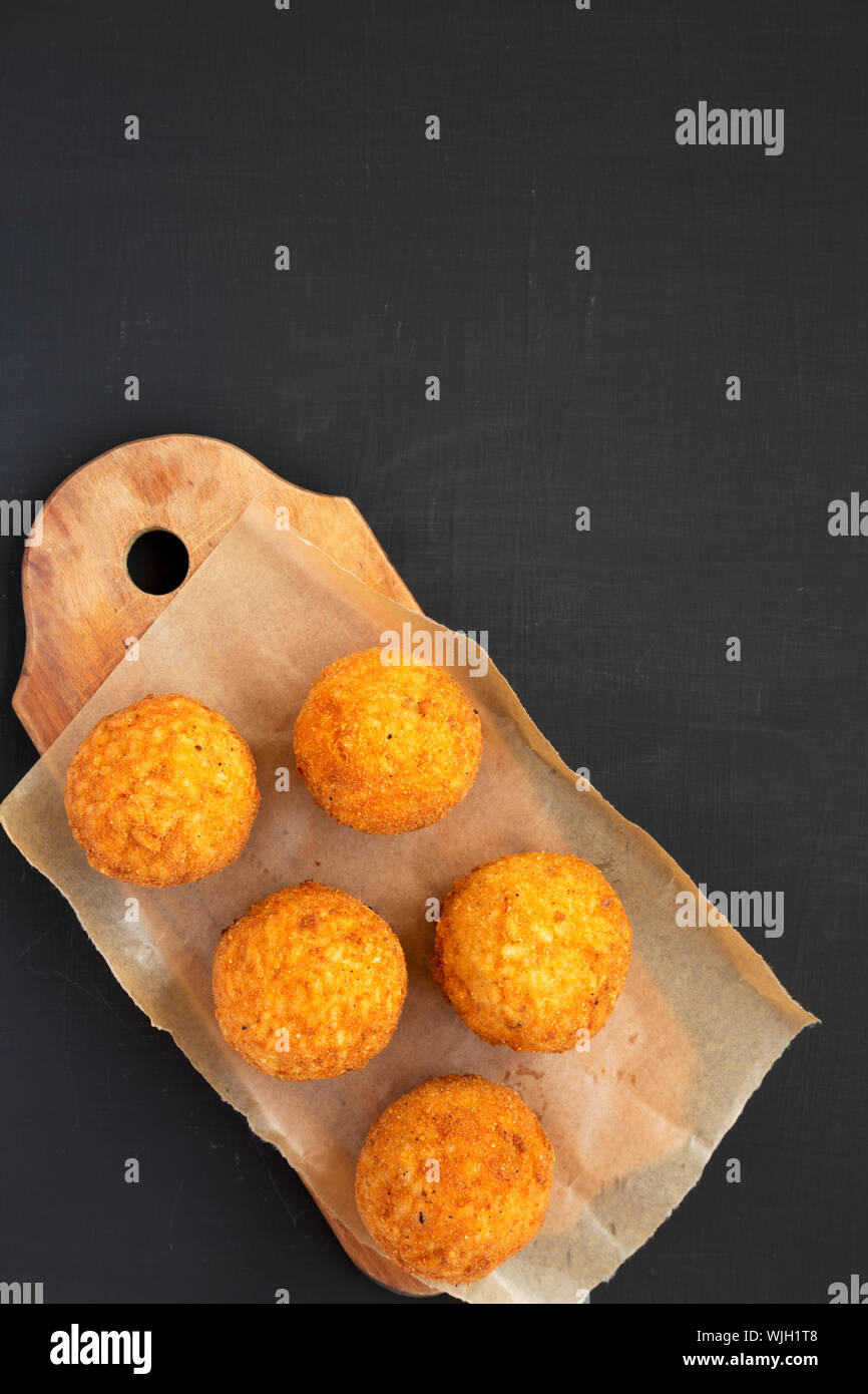 Homemade fried Arancini on a rustic wooden board on a black background ...
