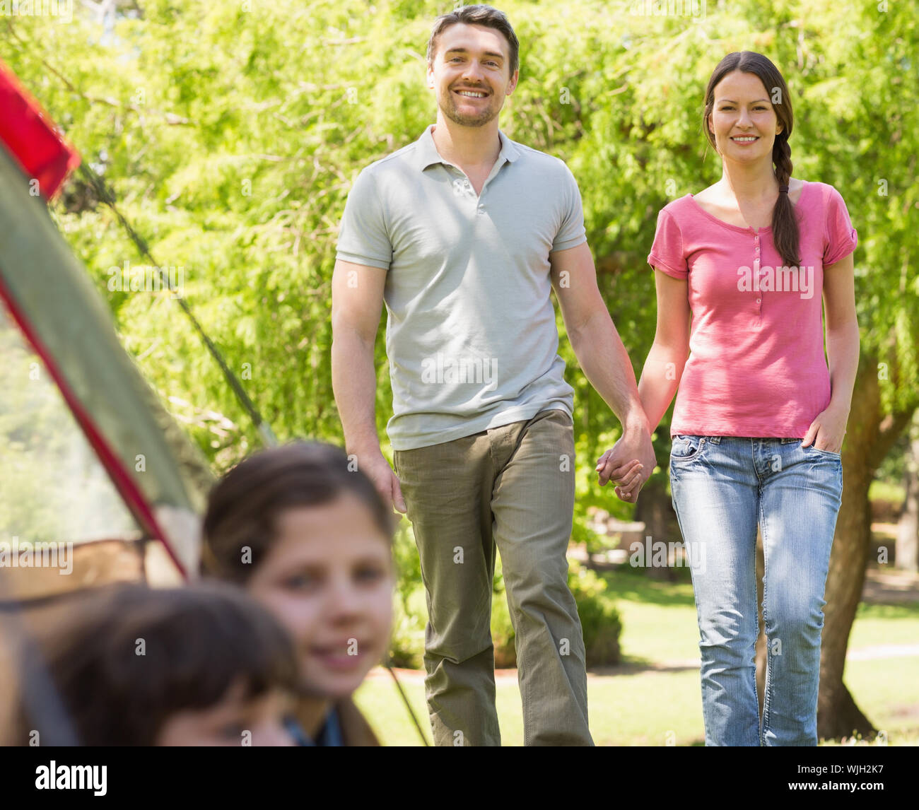Blurred kids in tent with portrait of couple in background at park ...