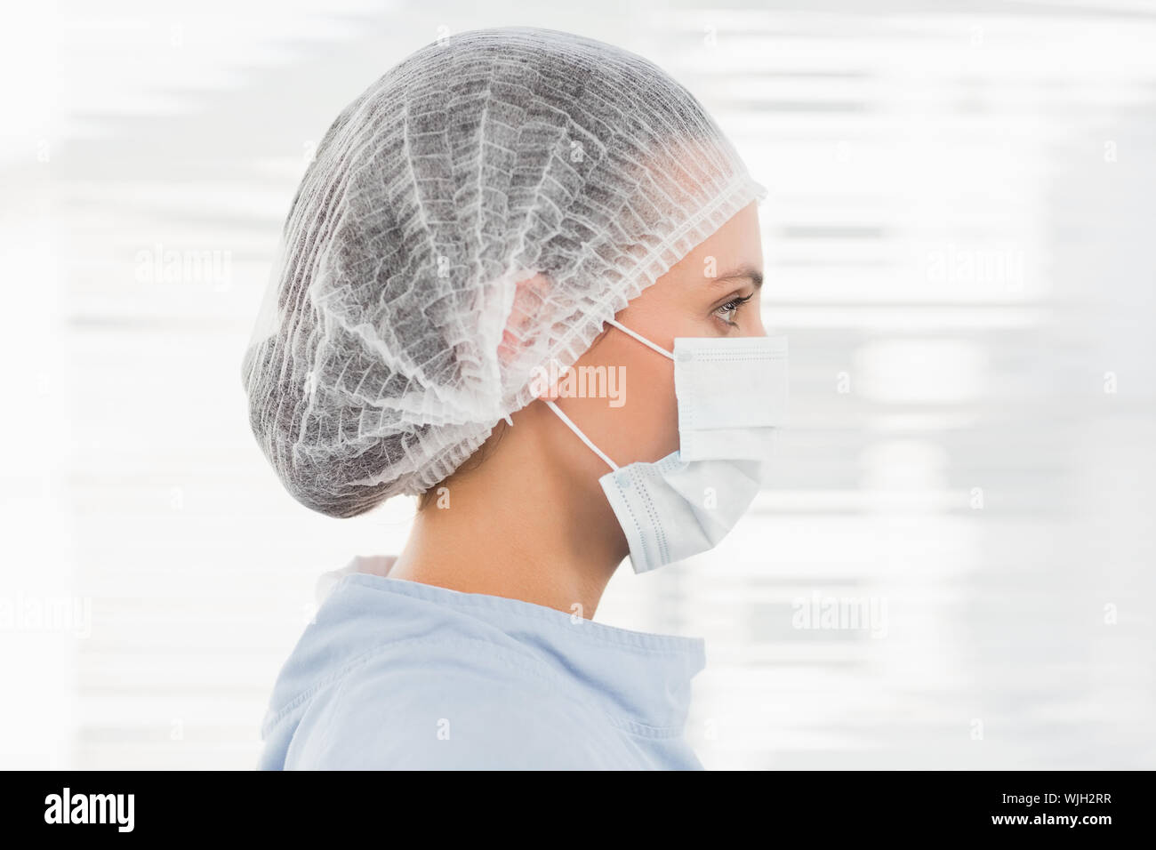 Close-up side view of a female surgeon wearing surgical cap and mask in ...