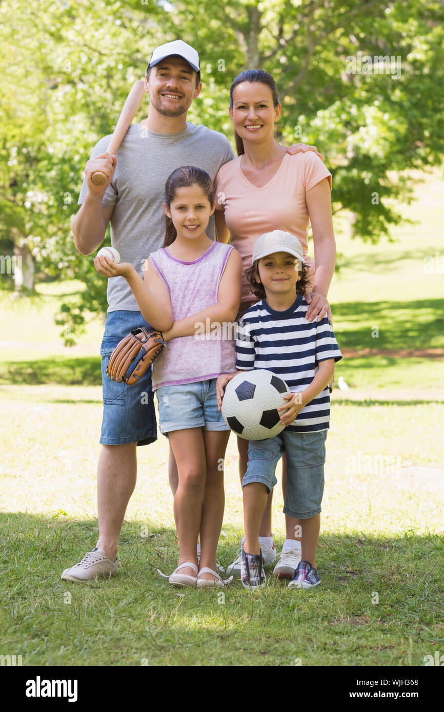 Full length portrait a family of four holding baseball bat and ball in ...