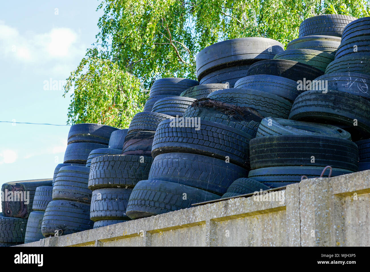 stack of old worn tires on a background of green trees Stock Photo - Alamy