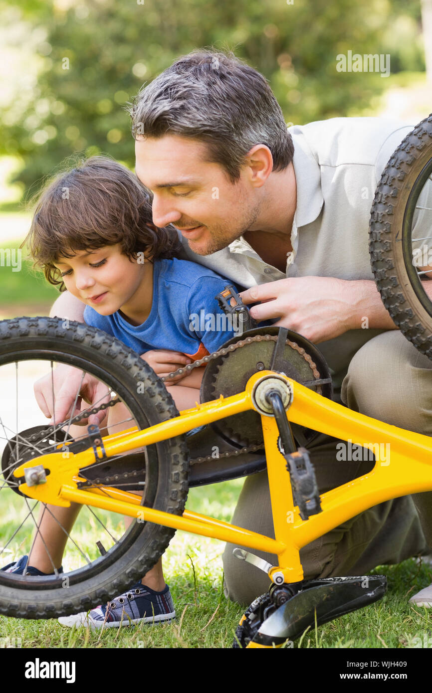 Side view of father and son fixing bike Stock Photo - Alamy