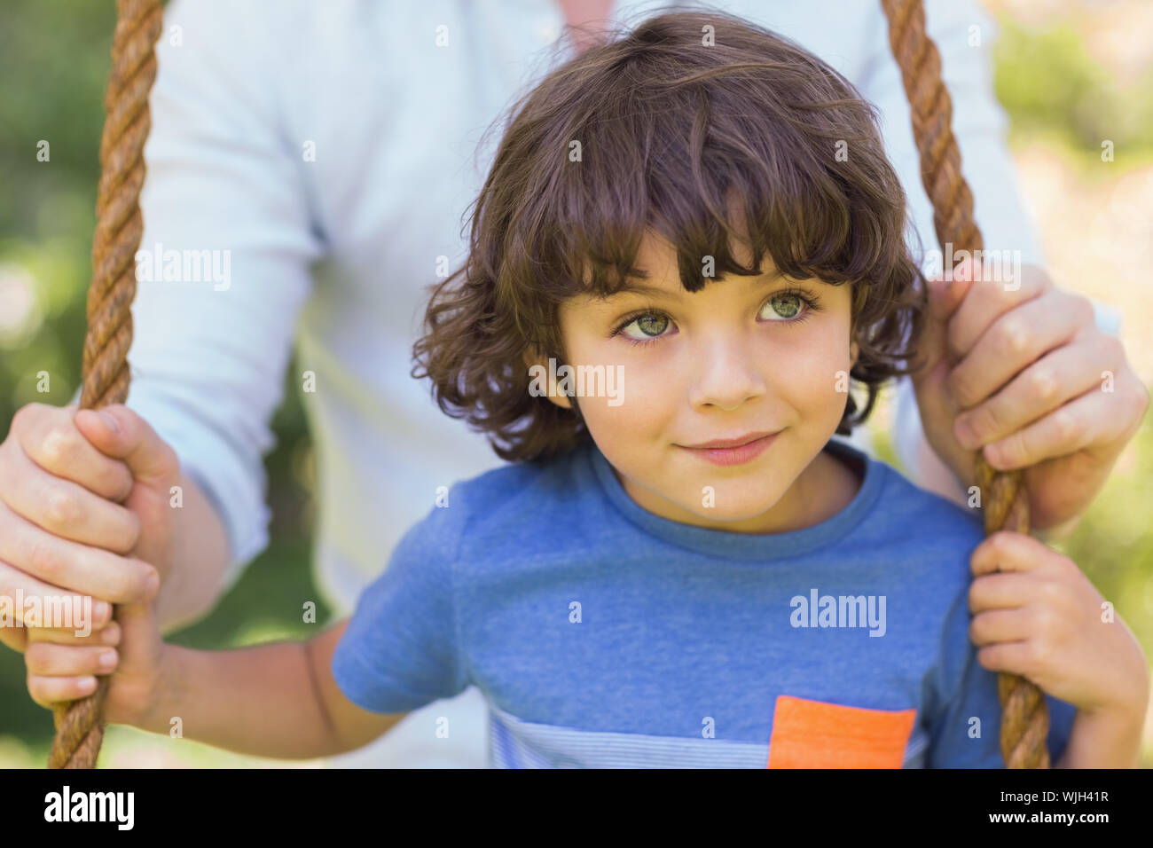 Close-up of a father pushing cute boy on swing in playground Stock ...