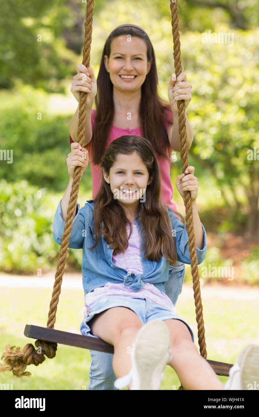 Happy mother pushing daughter on swing in playground Stock Photo - Alamy