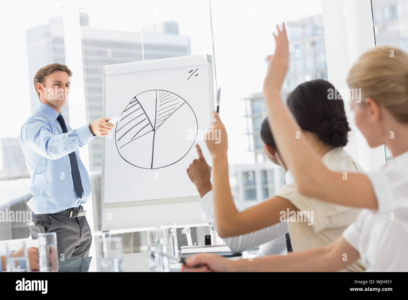 Businessman presenting pie chart to colleagues asking questions in the ...