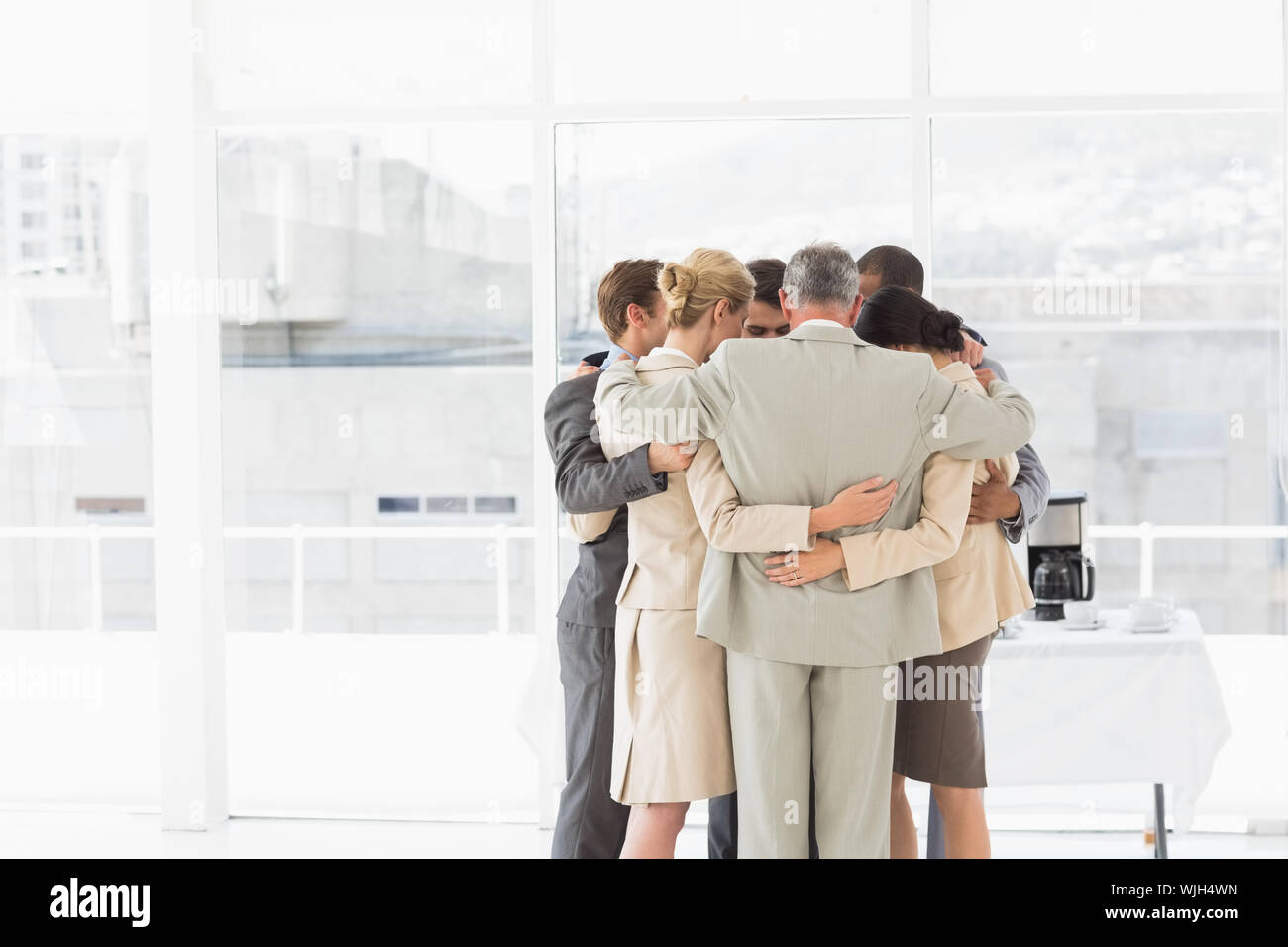 Business people hugging in a circle in the office Stock Photo - Alamy