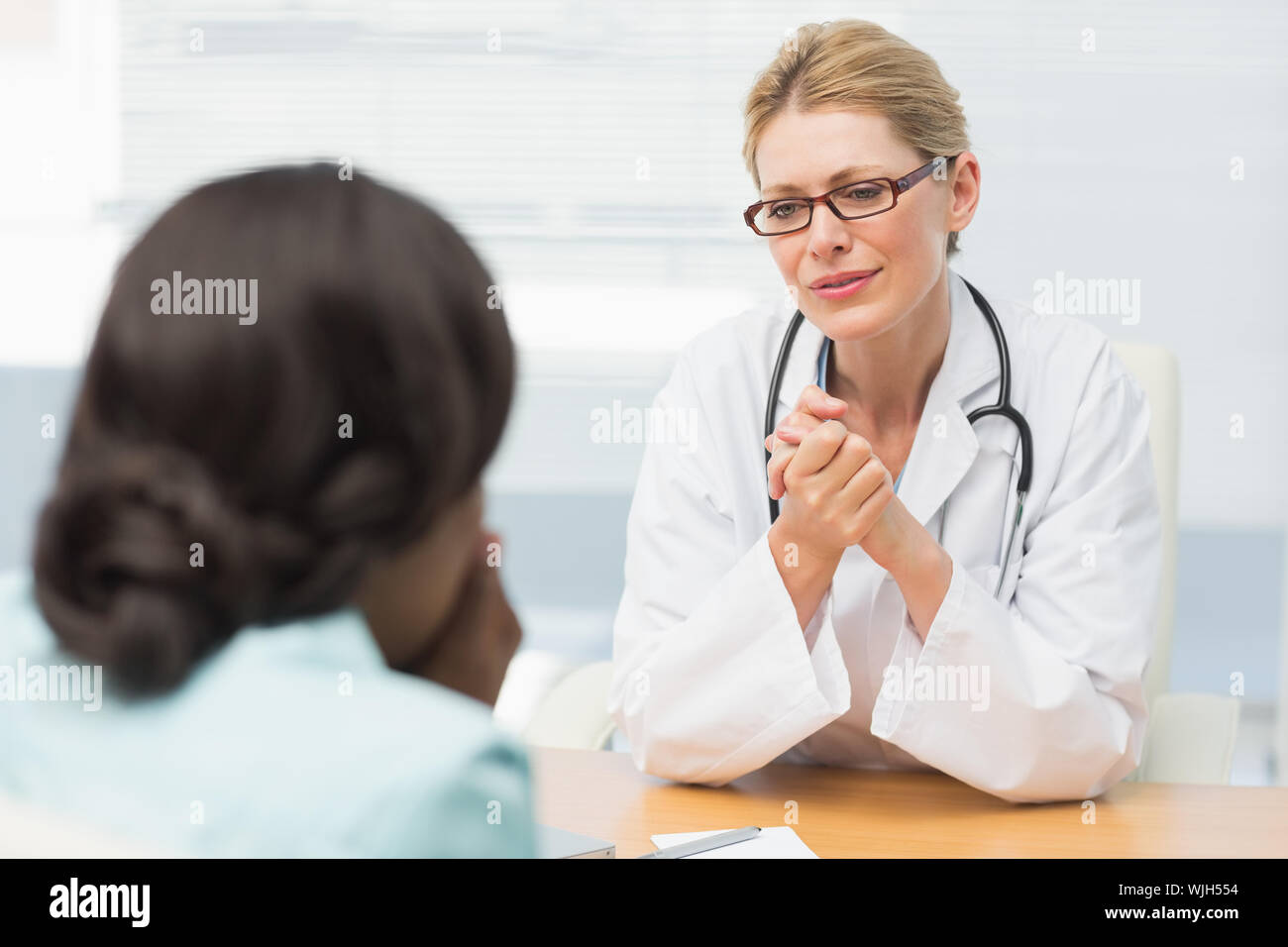 Concerned doctor listening to her patient in an office at the hospital ...