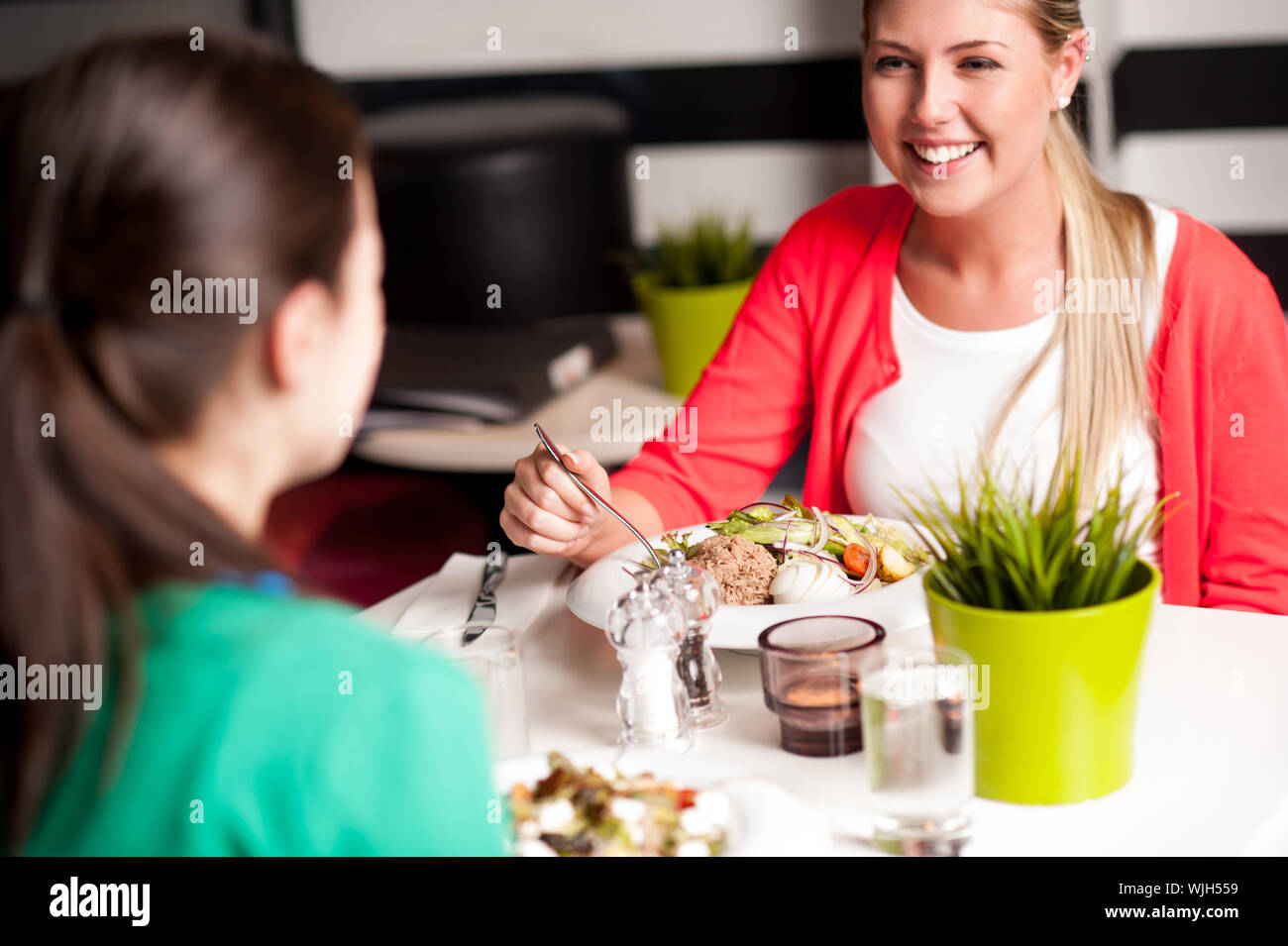 Cheerful young girls having dinner at a restaurant Stock Photo - Alamy