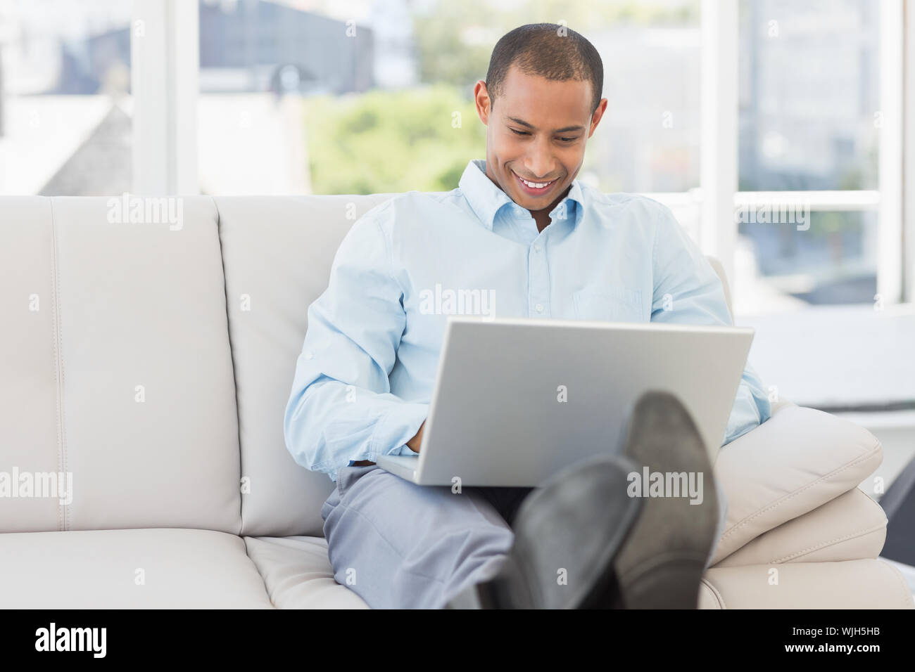 Happy businessman using laptop with his feet up in the office Stock ...