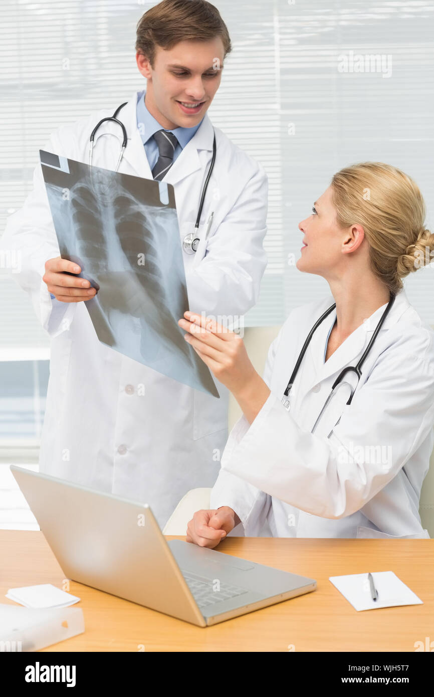 Smiling doctors examining an xray together in their office at the ...