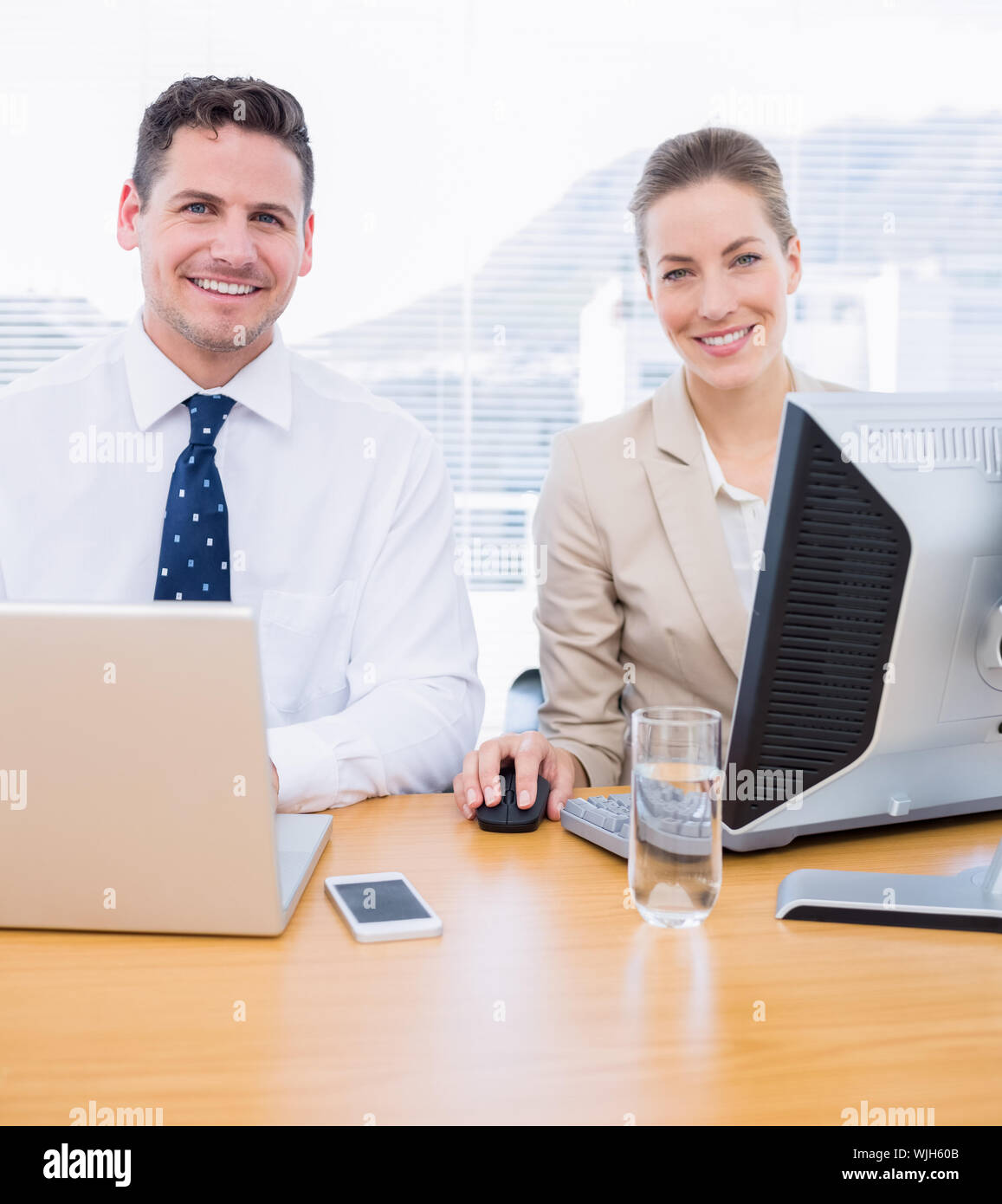 Smartly dressed young man and woman using computer and laptop at office ...