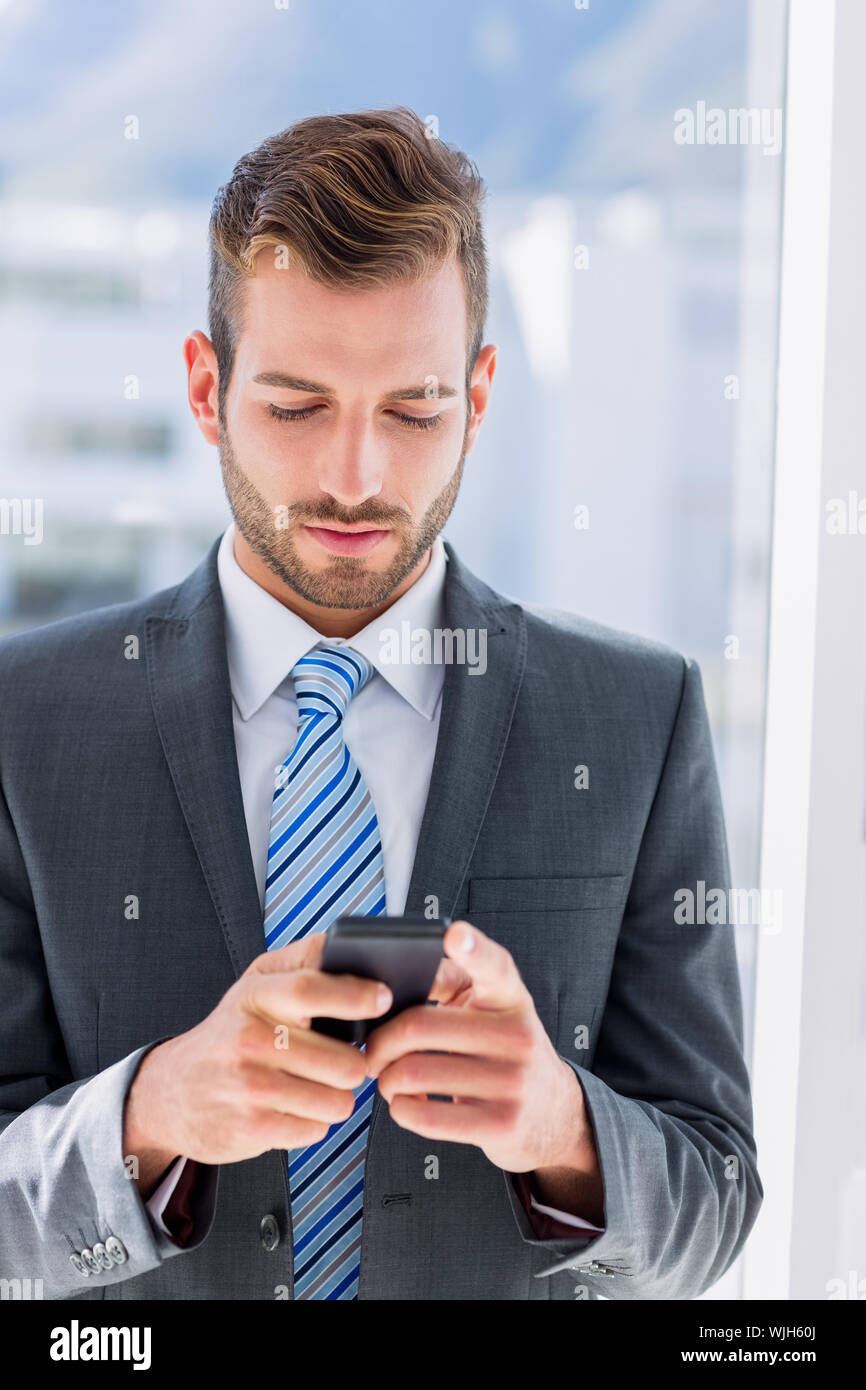 Handsome young businessman text messaging over blurred background in ...