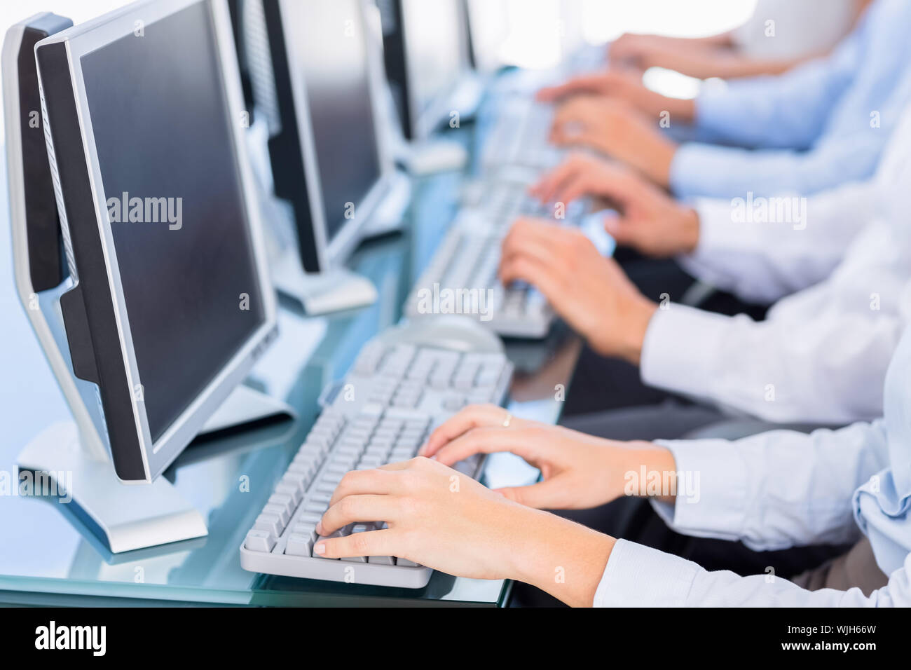 Side view of a group of business colleagues using computers at office ...
