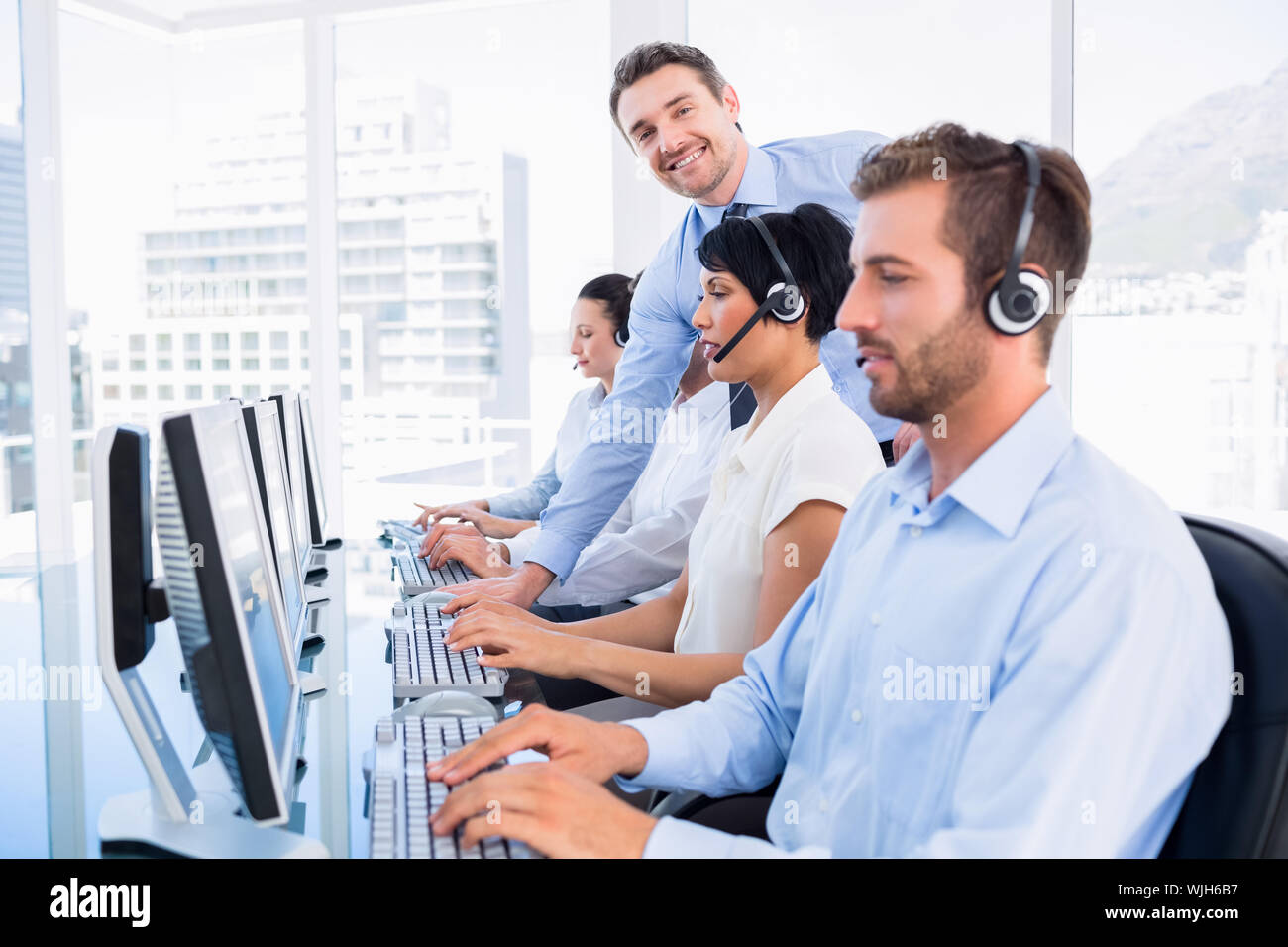 Side view of manager and executives with headsets using computers in ...