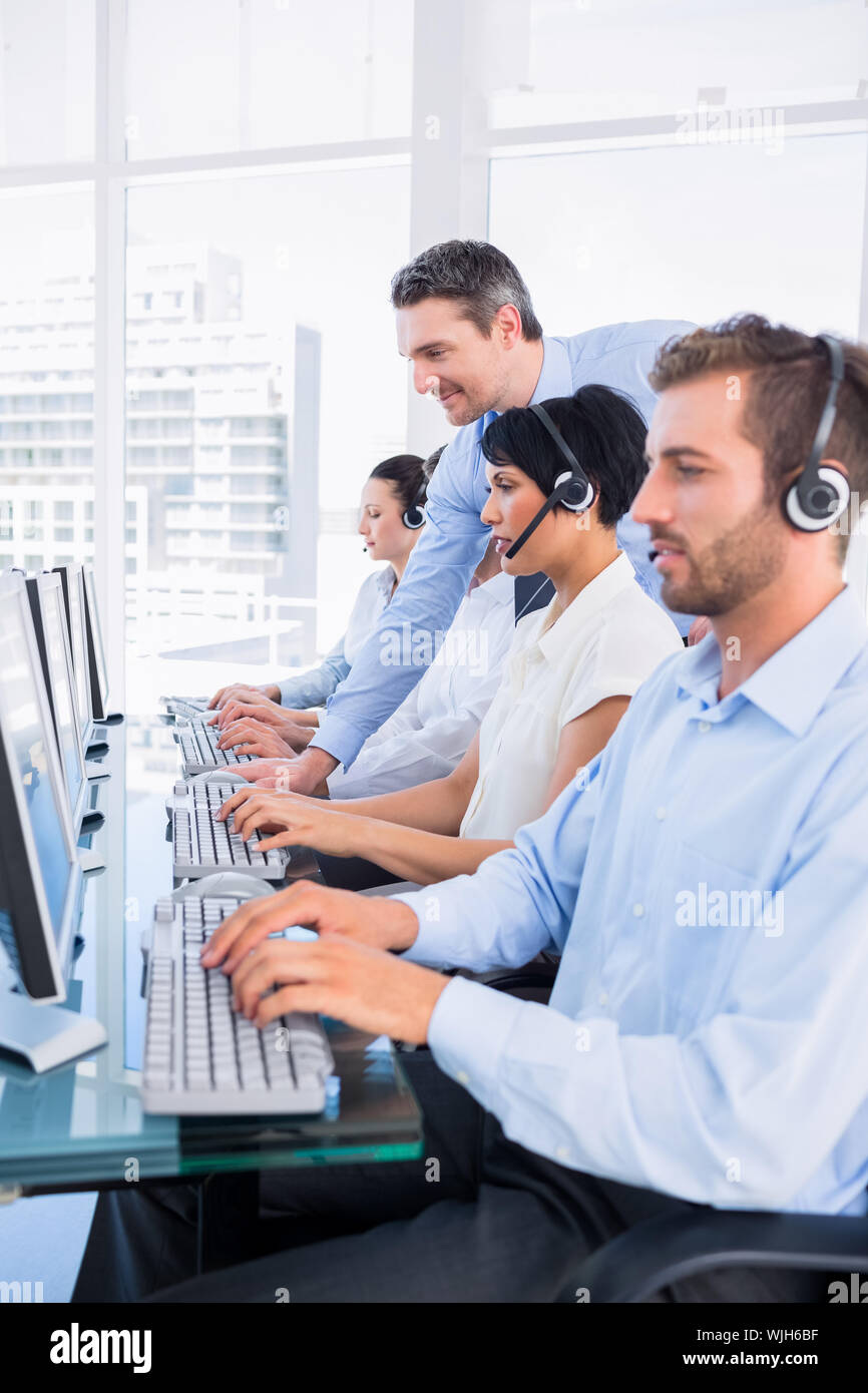 Side view of manager and executives with headsets using computers in ...
