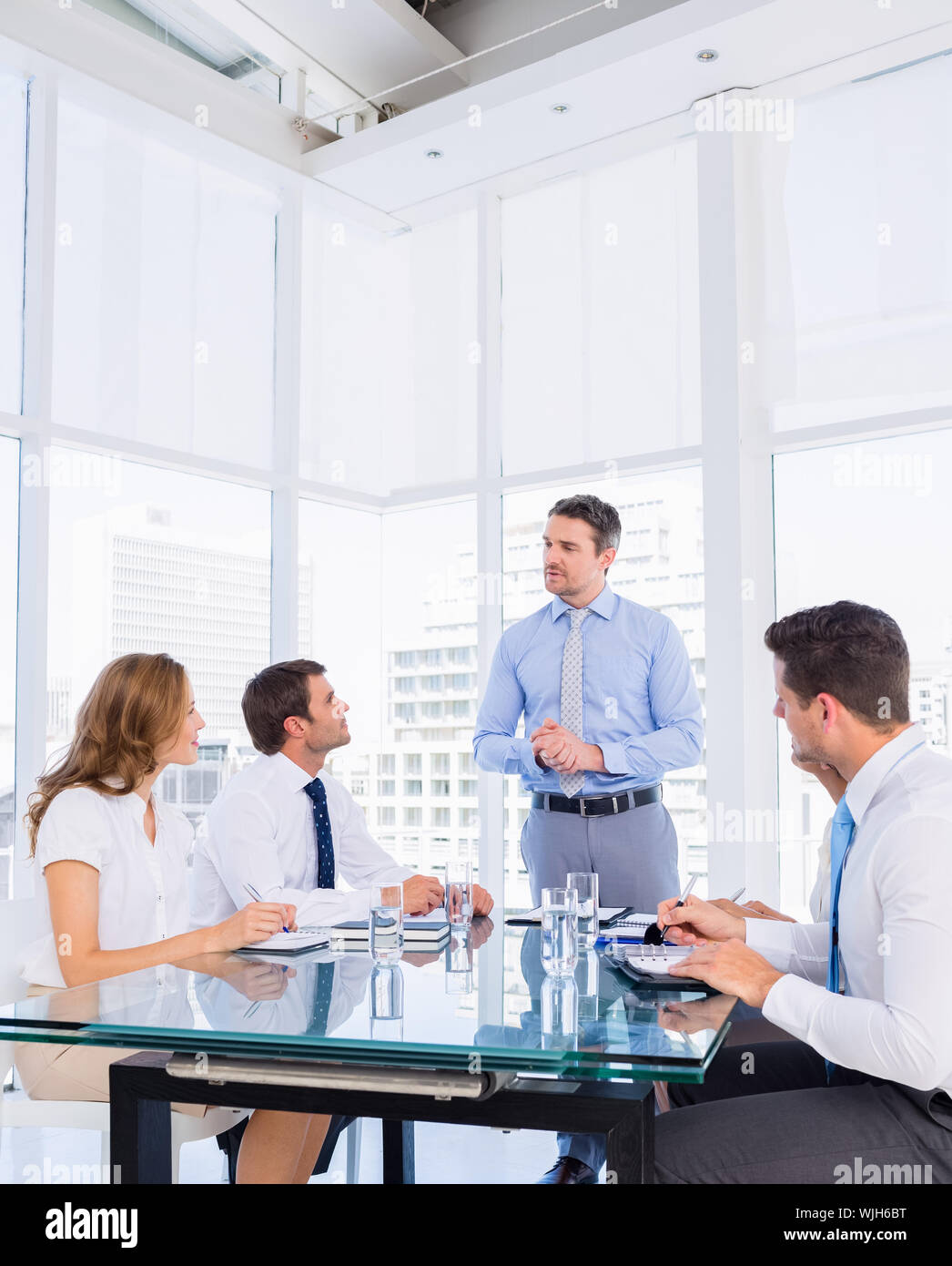 Smartly dressed young executives sitting around conference table in ...