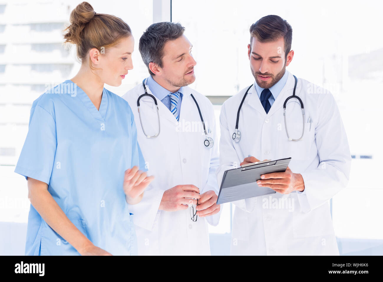 Two male doctors and female surgeon reading medical reports at the ...