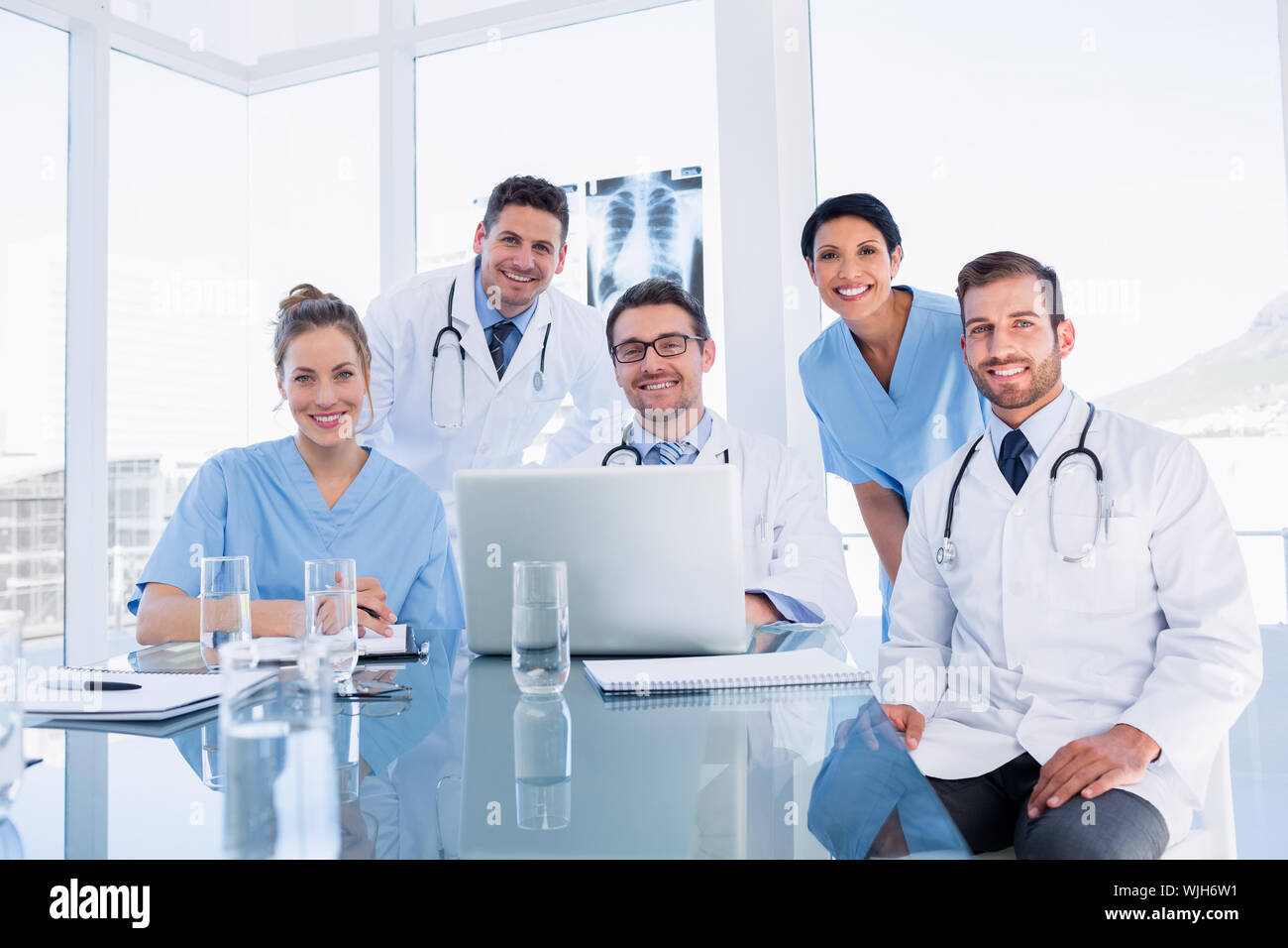 Portrait of a happy medical team using laptop together in the office ...
