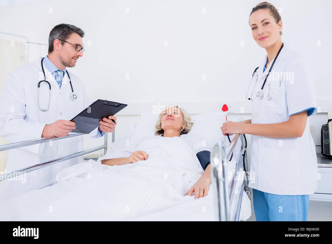 Portrait of two doctors visiting a female patient in the hospital Stock ...