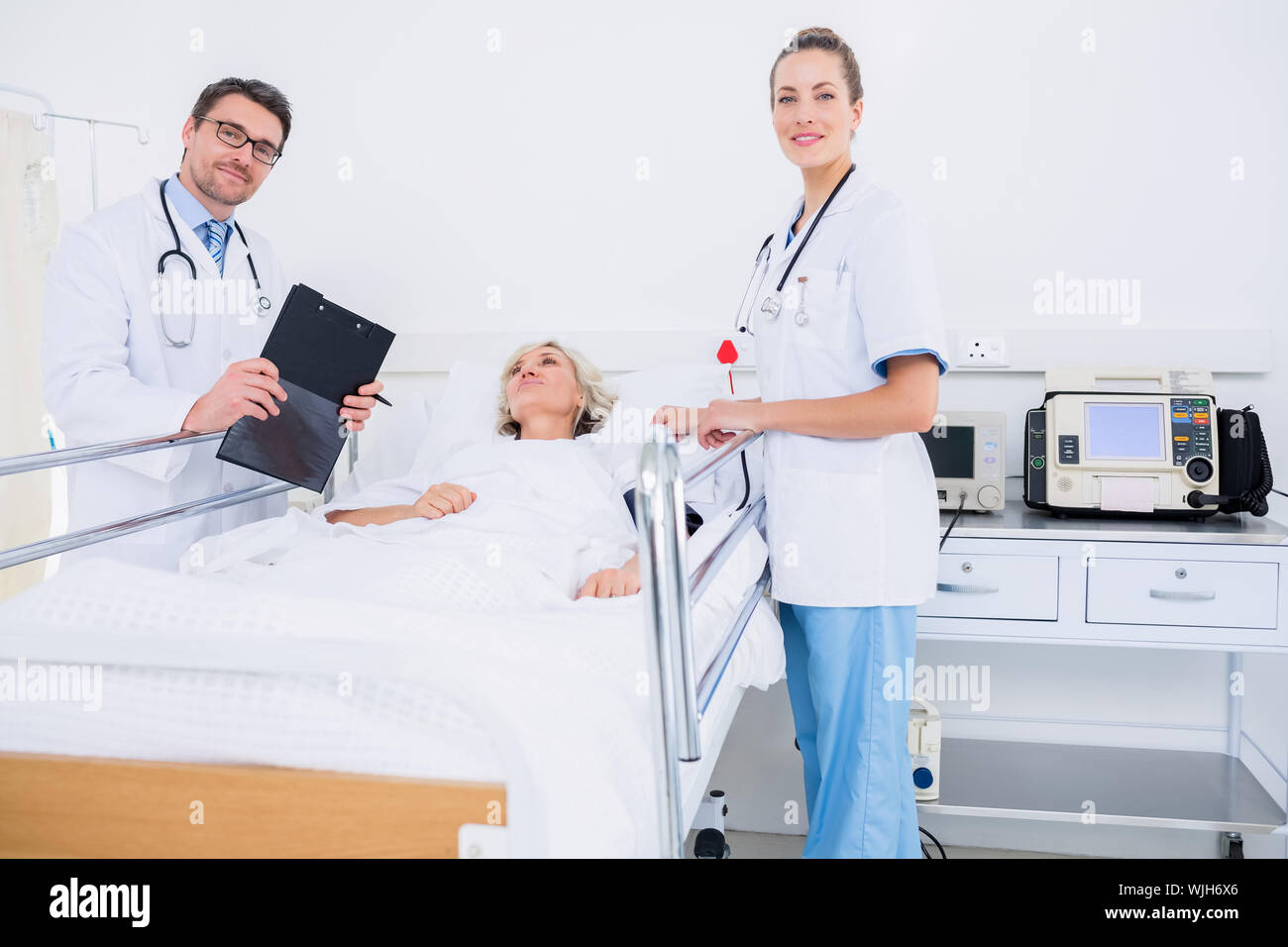 Portrait of two doctors visiting a female patient in the hospital Stock ...