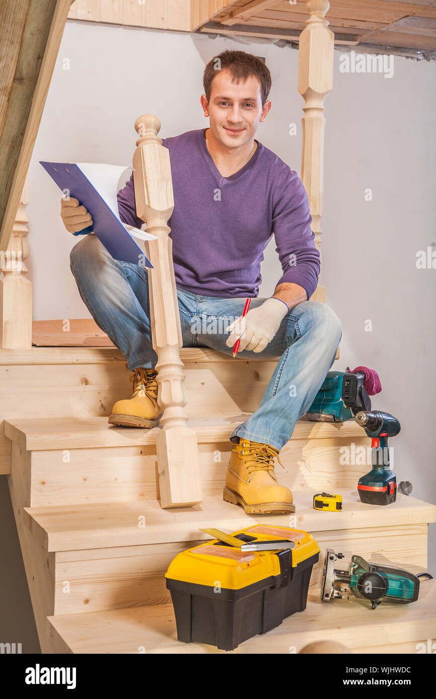 young carpenter sitting on step of of ladder with tools Stock Photo - Alamy