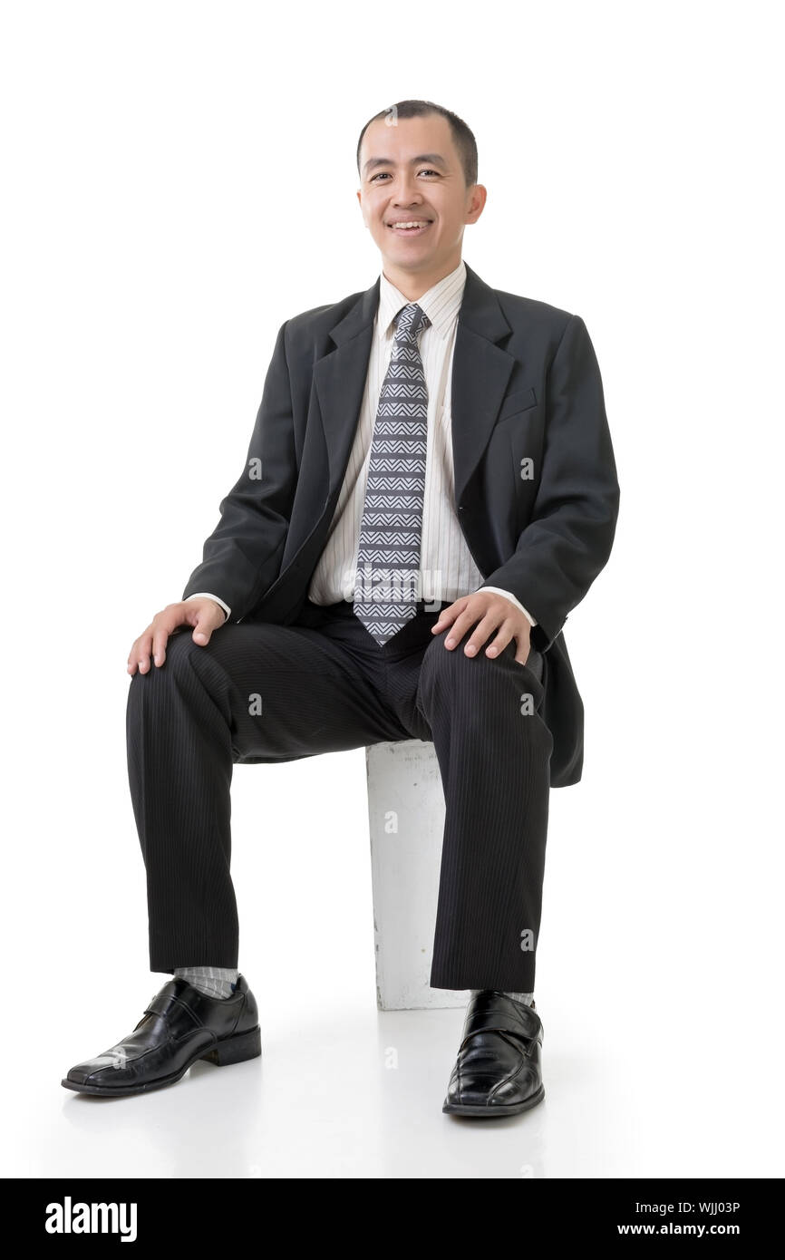 Friendly Asian business man sit on box, full length portrait on white ...