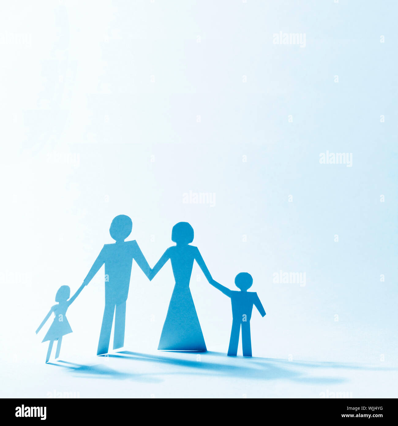 Paper family linked together over light background Stock Photo - Alamy