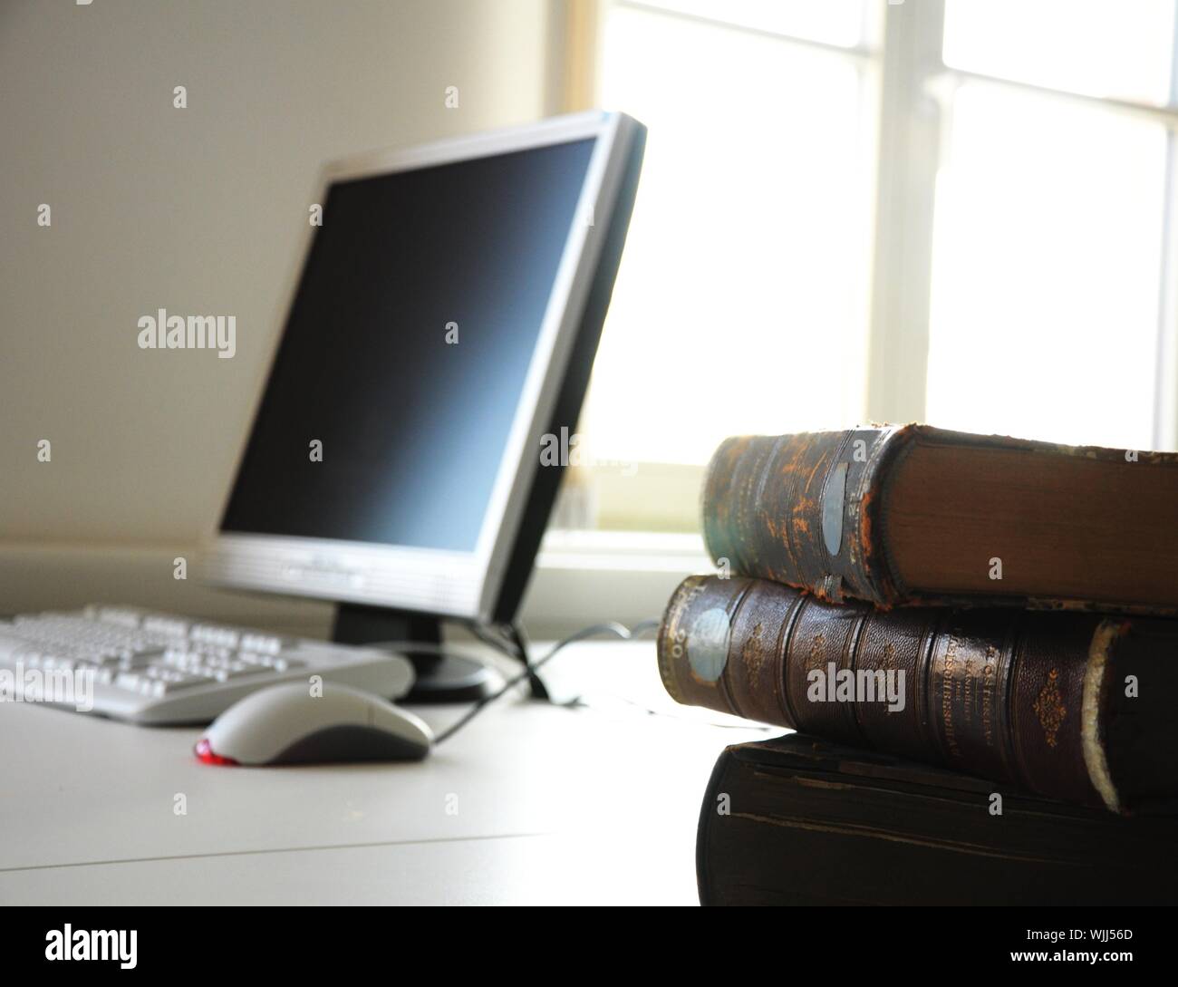 old books and computer on a desk in a library Stock Photo - Alamy