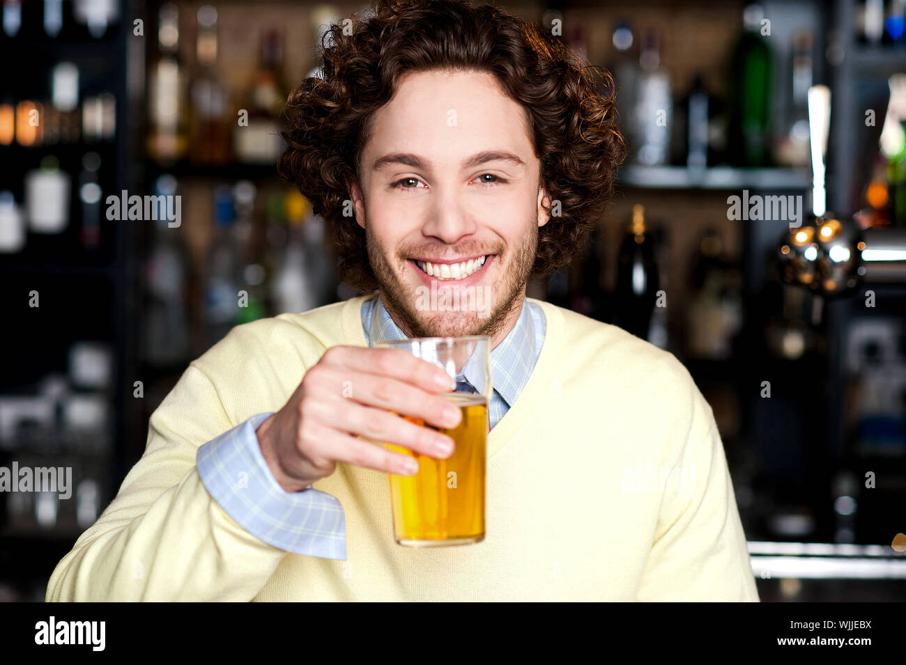 Handsome young man at bar holding glass of beer Stock Photo - Alamy
